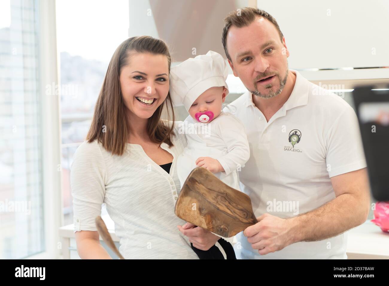 Happy parents standing in the kitchen with their baby girl chef Stock ...