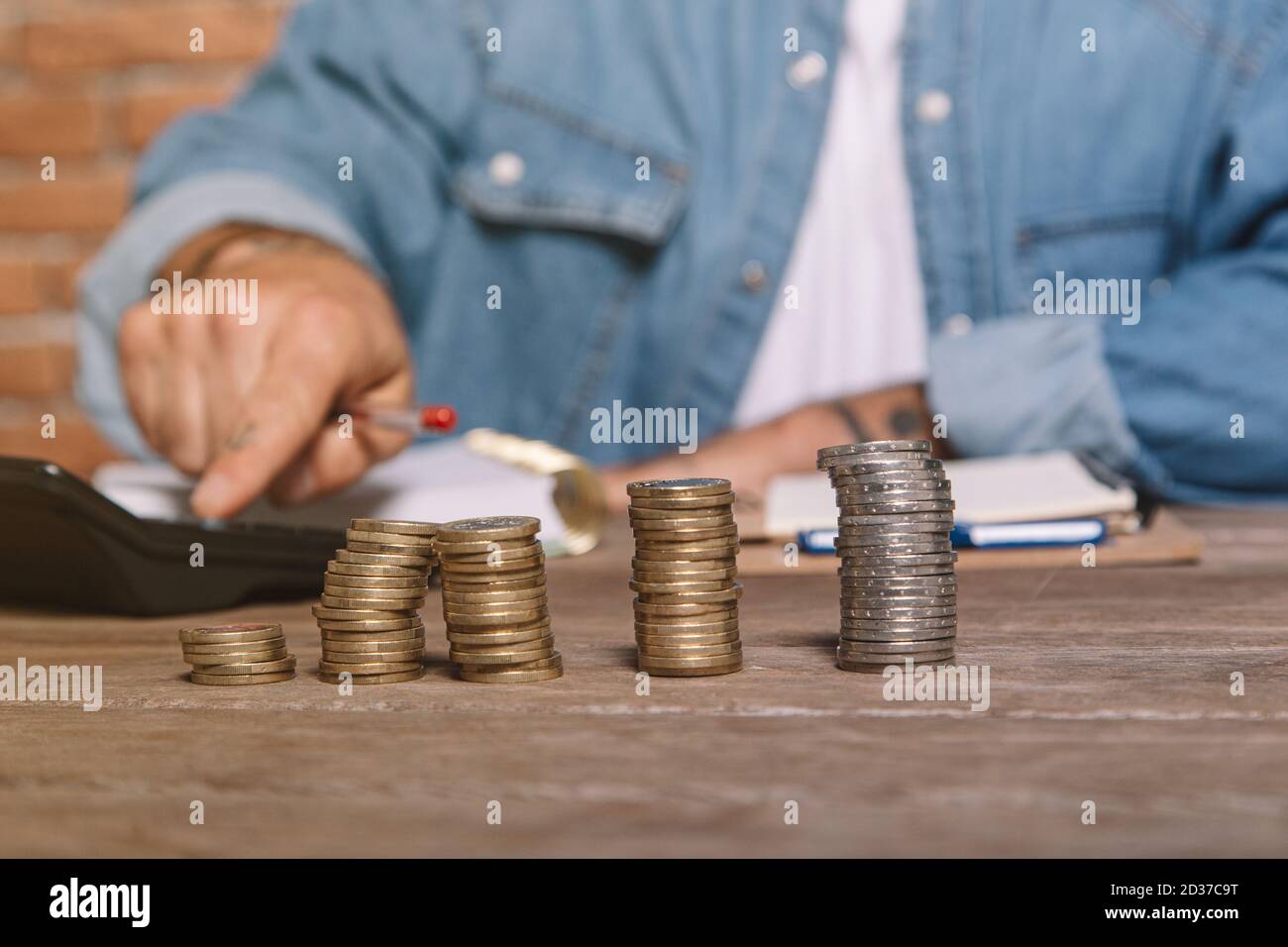 Man with a calculator and a stack of coins calculating money savings ...