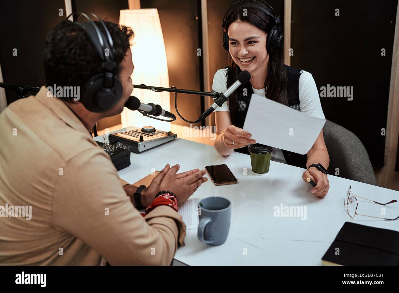 Portait of happy female radio host smiling, talking to male guest ...