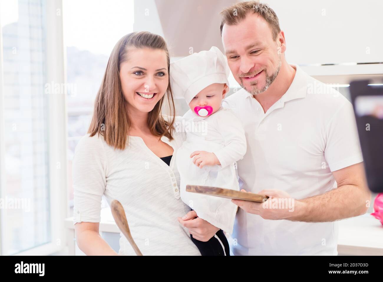 Happy parents standing in the kitchen with their baby girl chef Stock ...