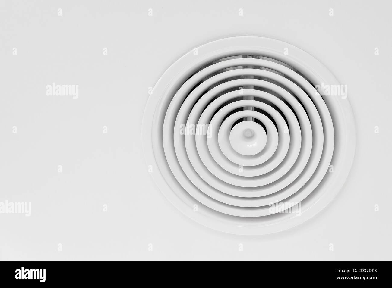 Round ventilation diffuser mounted in white ceiling, close-up photo ...