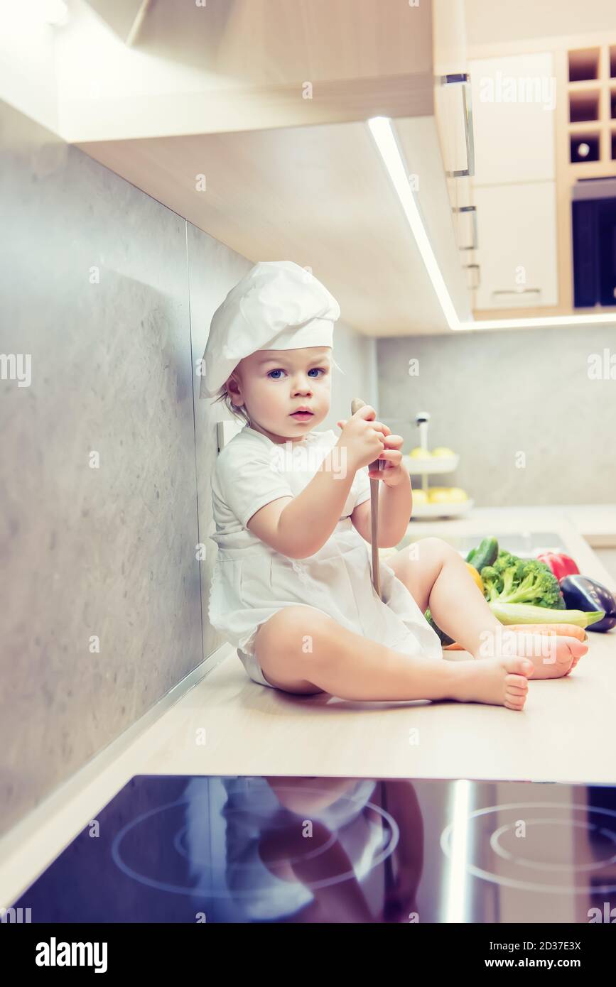 Baby boy sitting among vegetables in the kitchen and prepares for ...