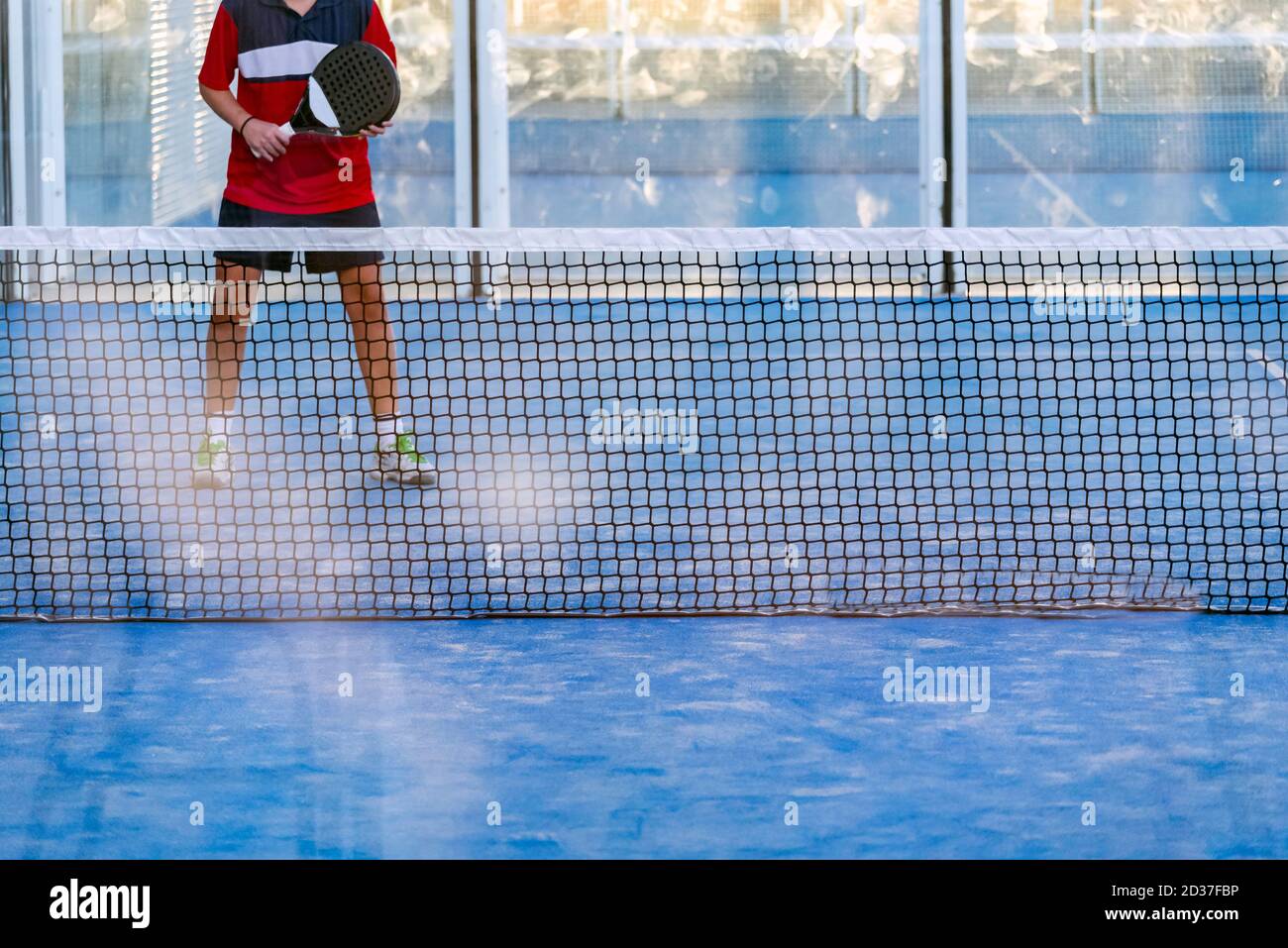 Paddle court with the net and a player with his paddle in his hand ...
