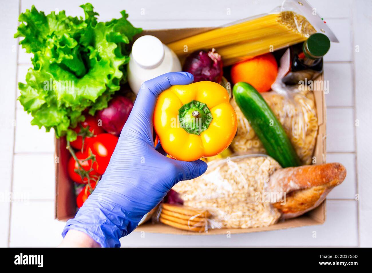Volunteer in gloves giving food in a donation cardboard box with ...