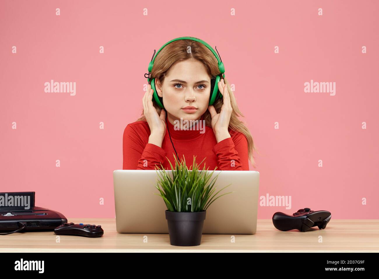 woman in headphones with gamepad in front of laptop sit at table ...