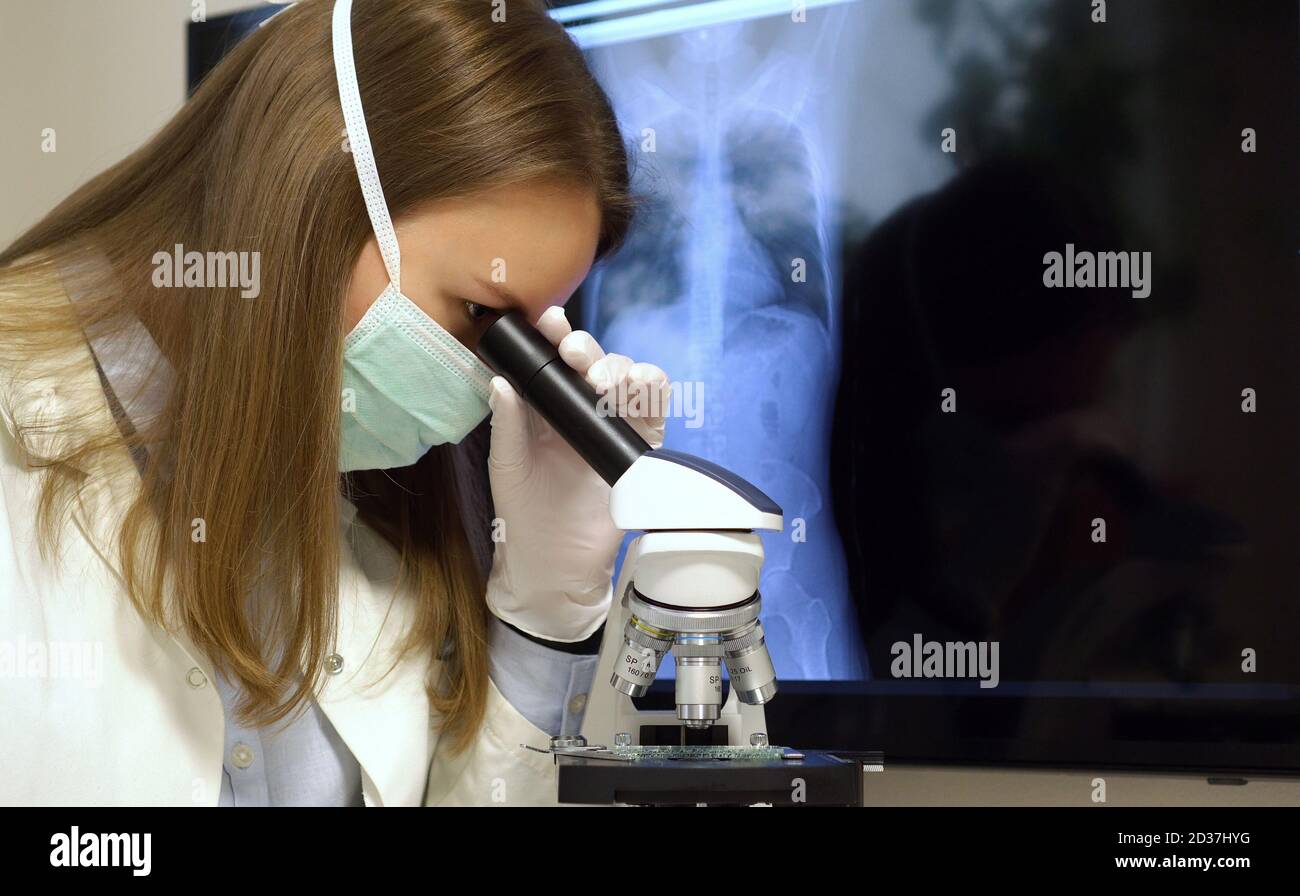 Scientist in medical mask in laboratory. Chest x-ray film on background ...
