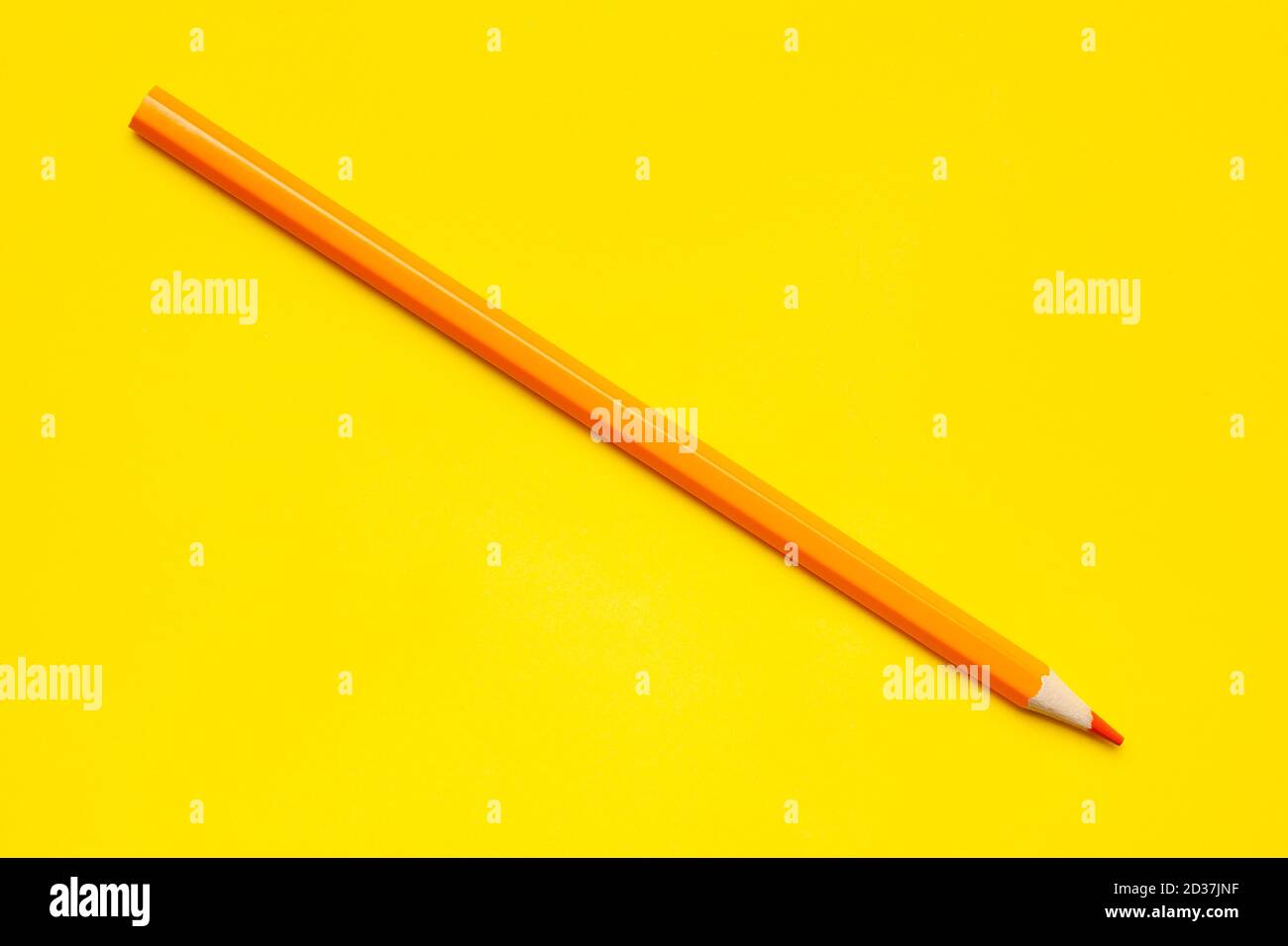 diagonal orange sharp wooden pencil on a bright yellow background ...