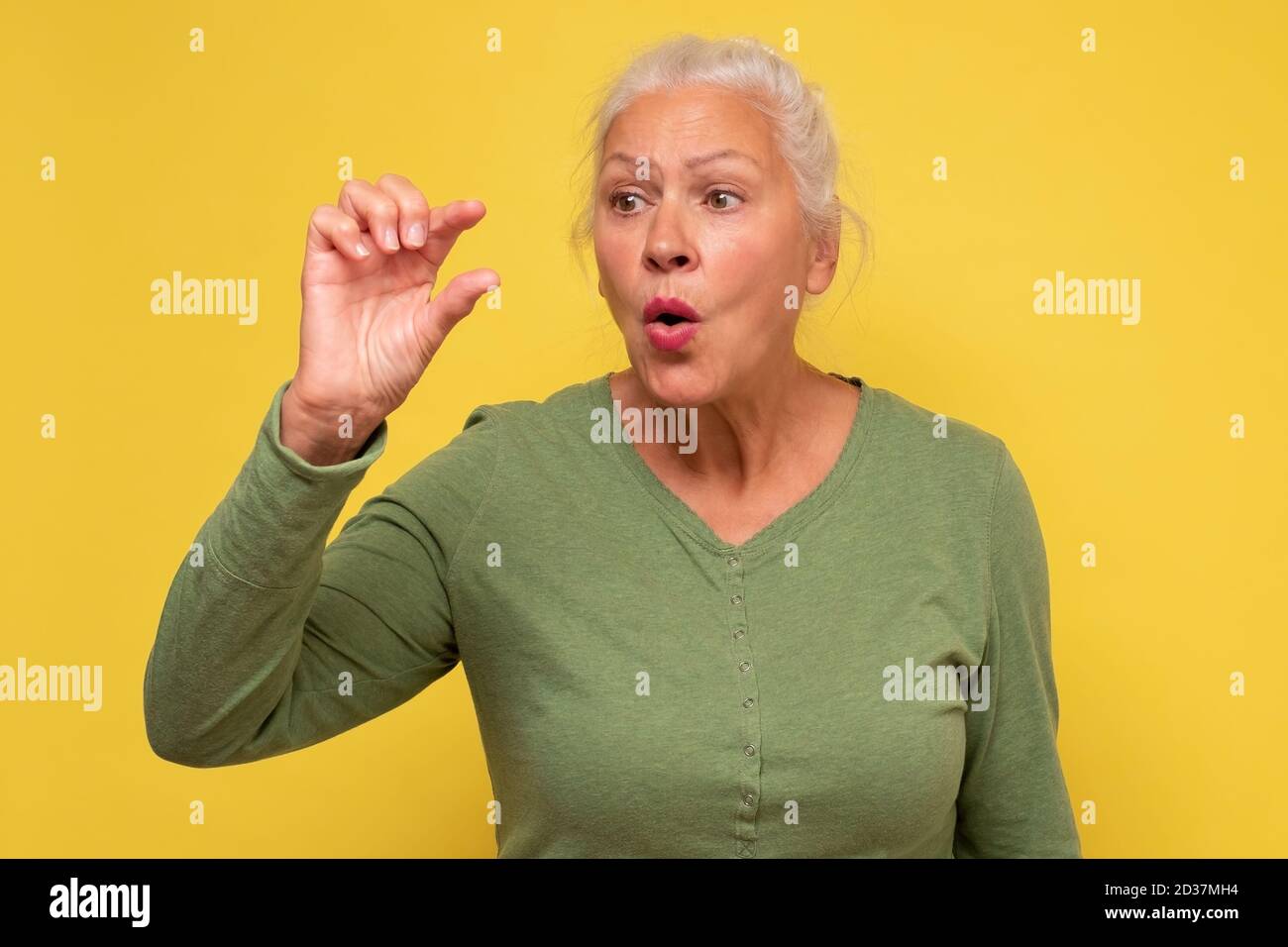 Surprised senior woman shows something small with hands Stock Photo - Alamy