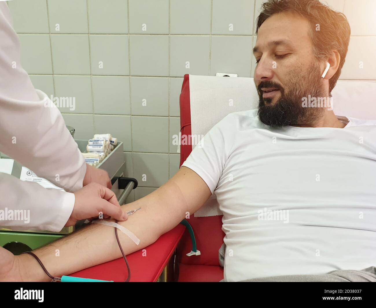 Blood donor sitting in medical chair while giving blood. Blood donation ...