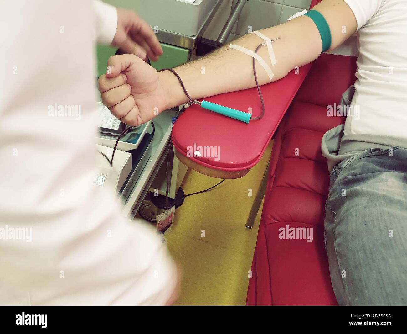 Blood donor sitting in medical chair while giving blood. Blood donation ...