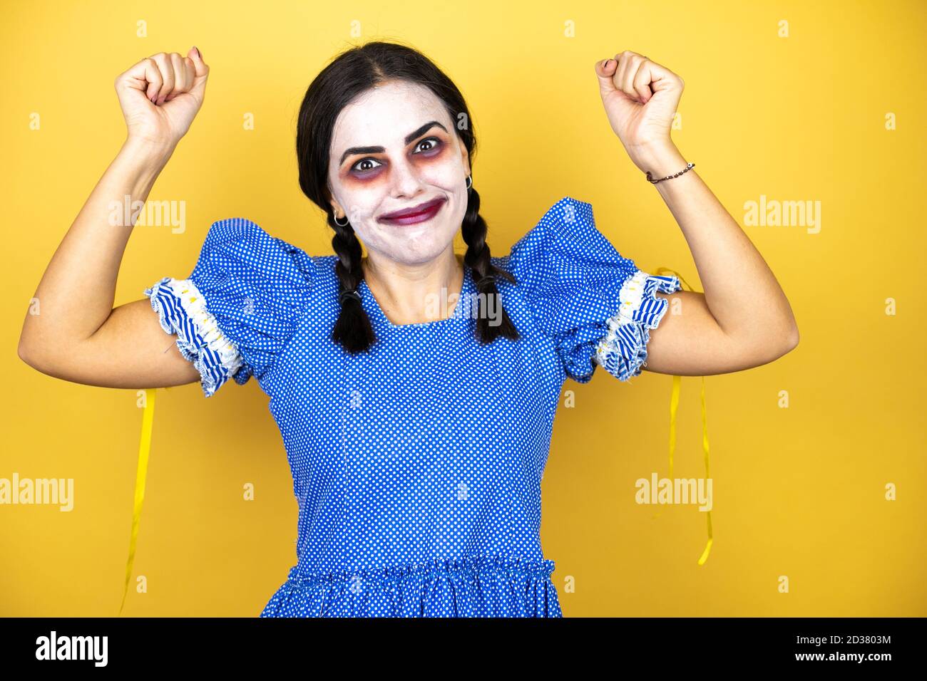 woman wearing a scary doll halloween costume over yellow background ...