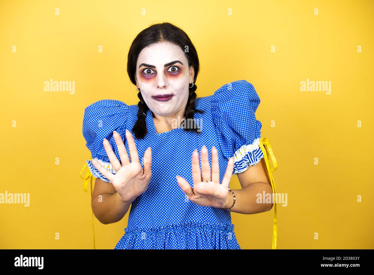 woman wearing a scary doll halloween costume over yellow background ...