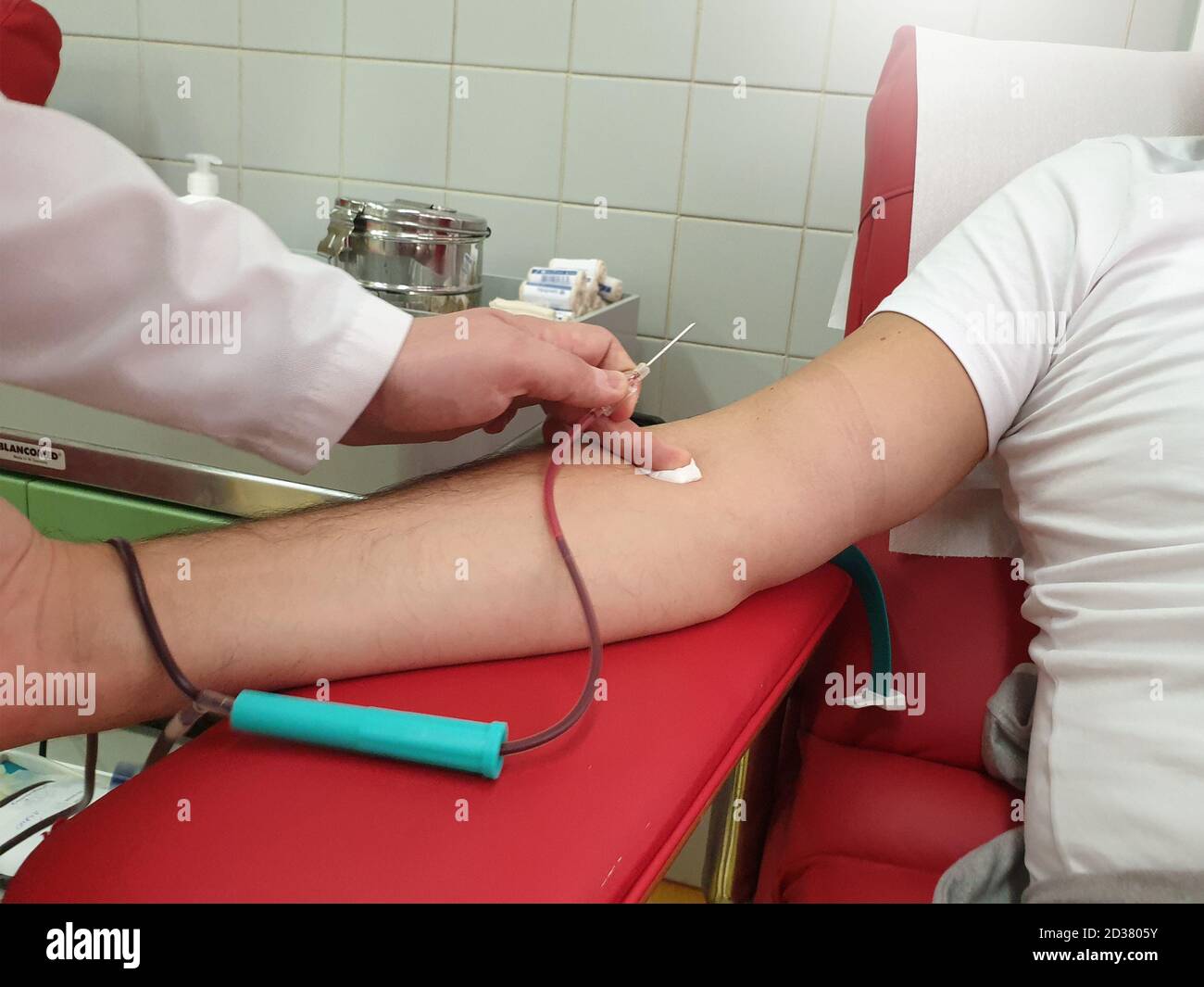 Blood donor sitting in medical chair while giving blood. Blood donation ...