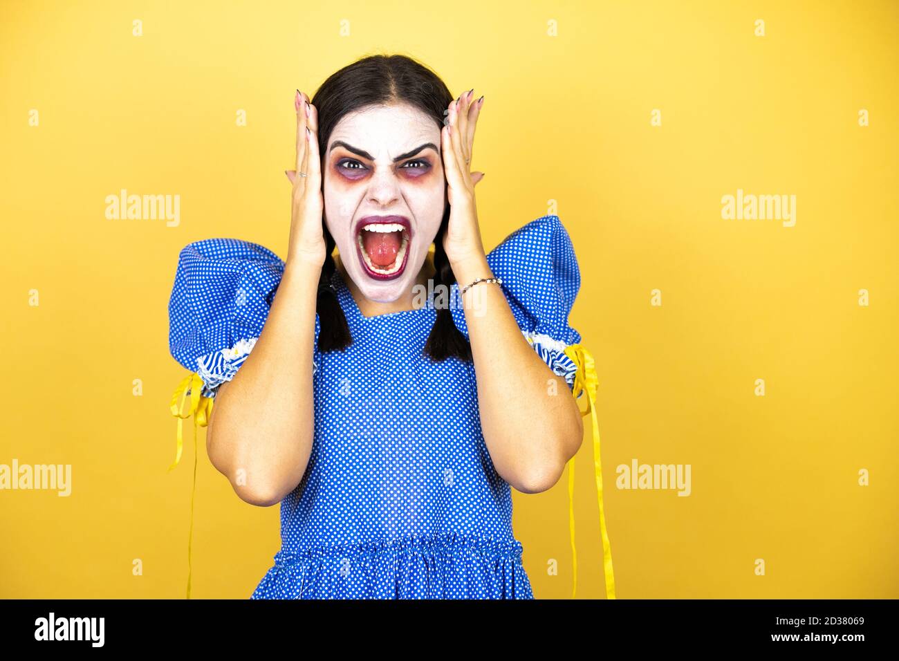 woman wearing a scary doll halloween costume over yellow background ...