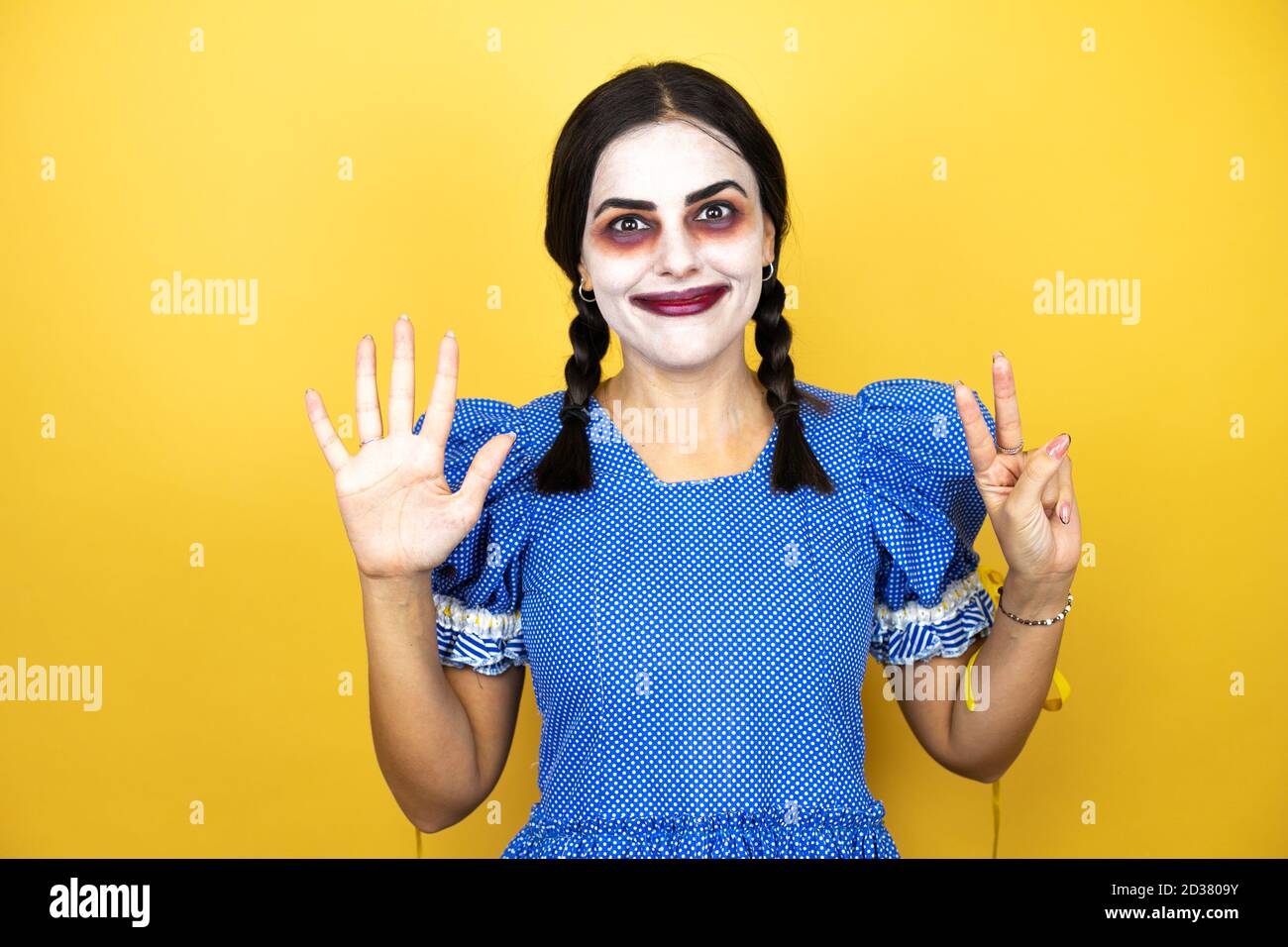 woman wearing a scary doll halloween costume over yellow background ...