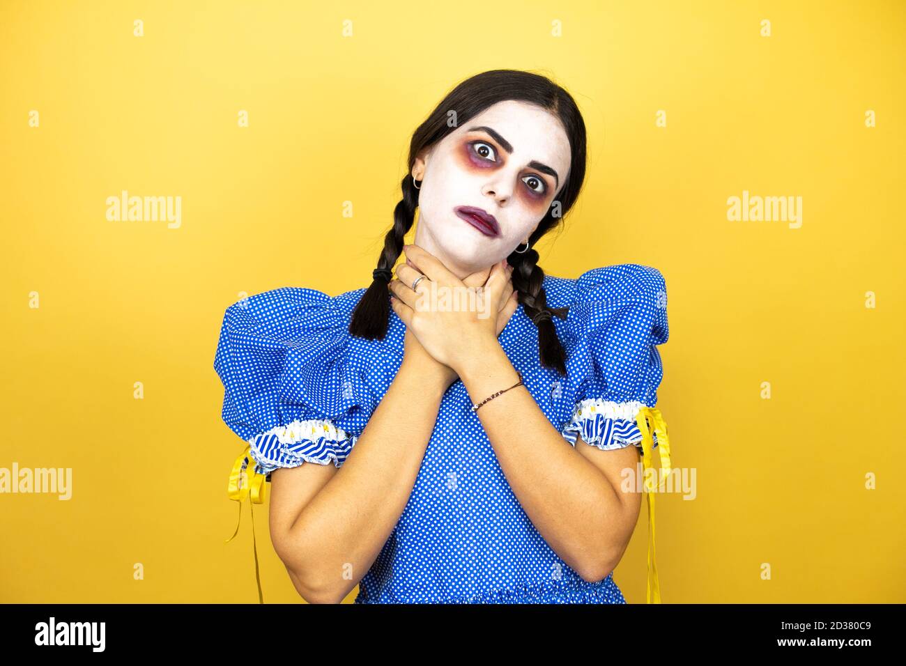 woman wearing a scary doll halloween costume over yellow background ...