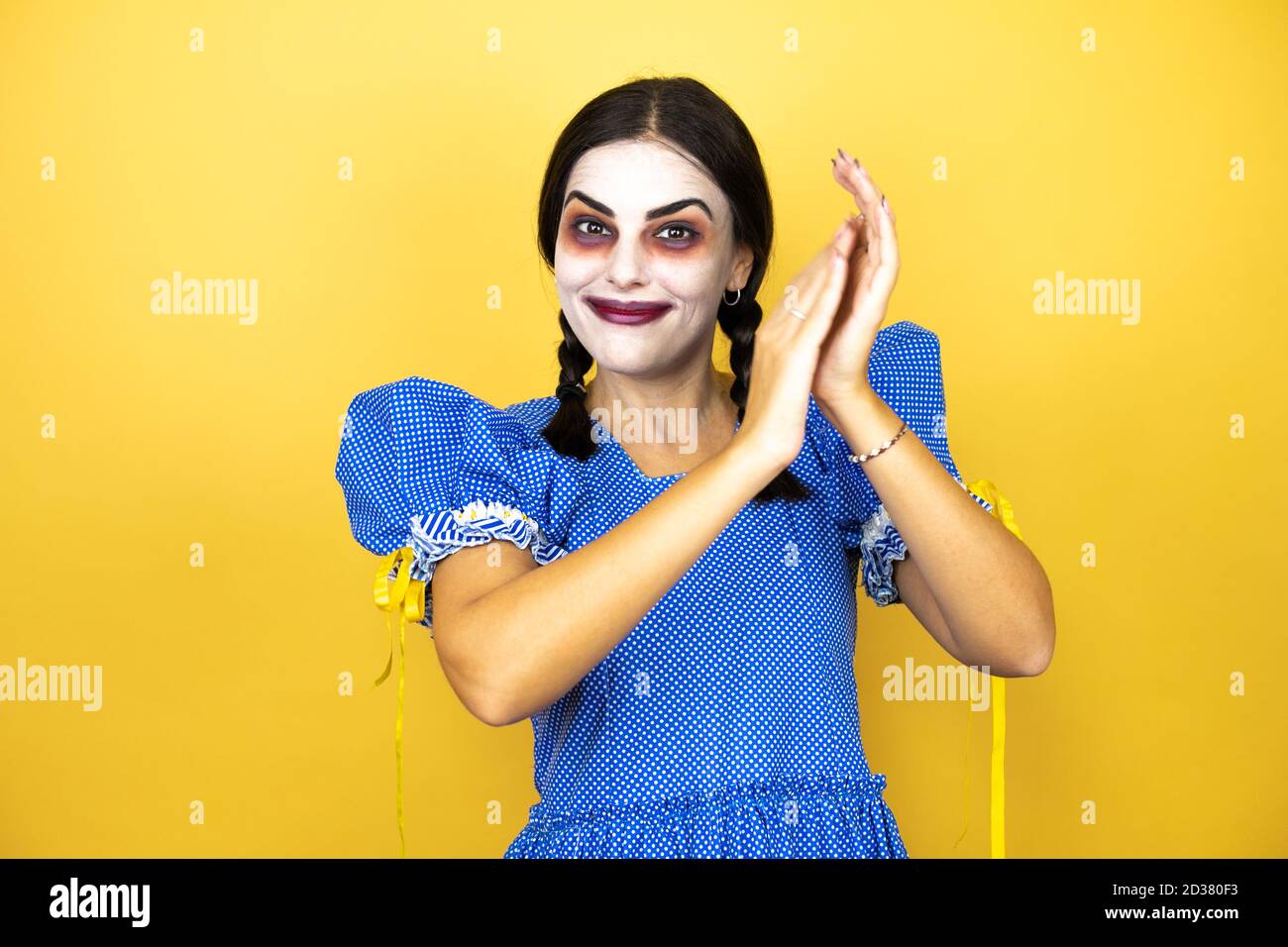 woman wearing a scary doll halloween costume over yellow background ...
