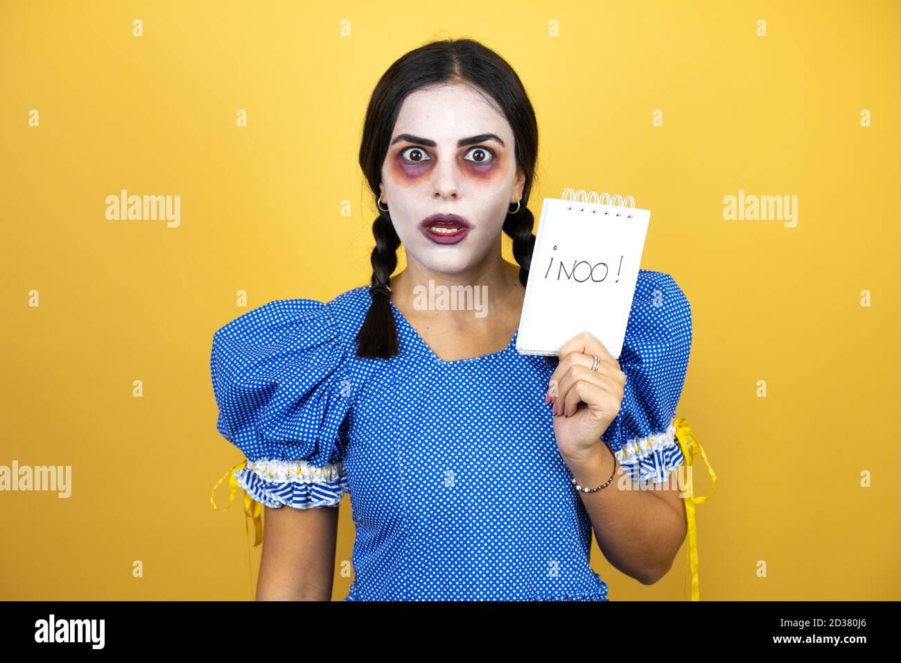 woman wearing a scary doll halloween costume over yellow background ...