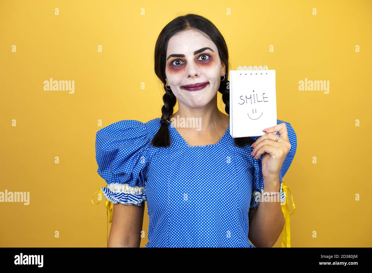 woman wearing a scary doll halloween costume over yellow background ...