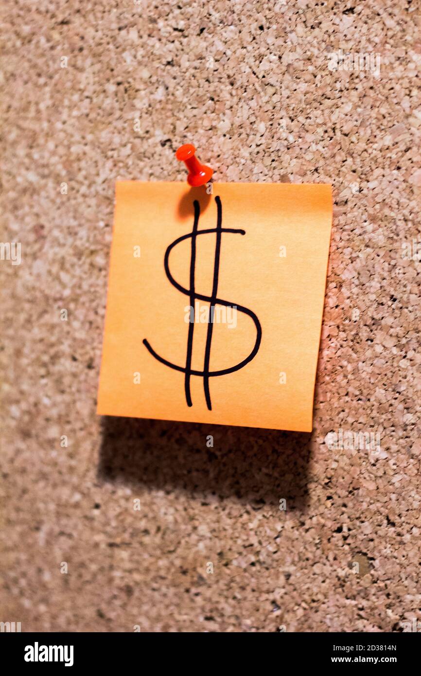 Vertical shot of a sticky note with a dollar sign on a cork board ...