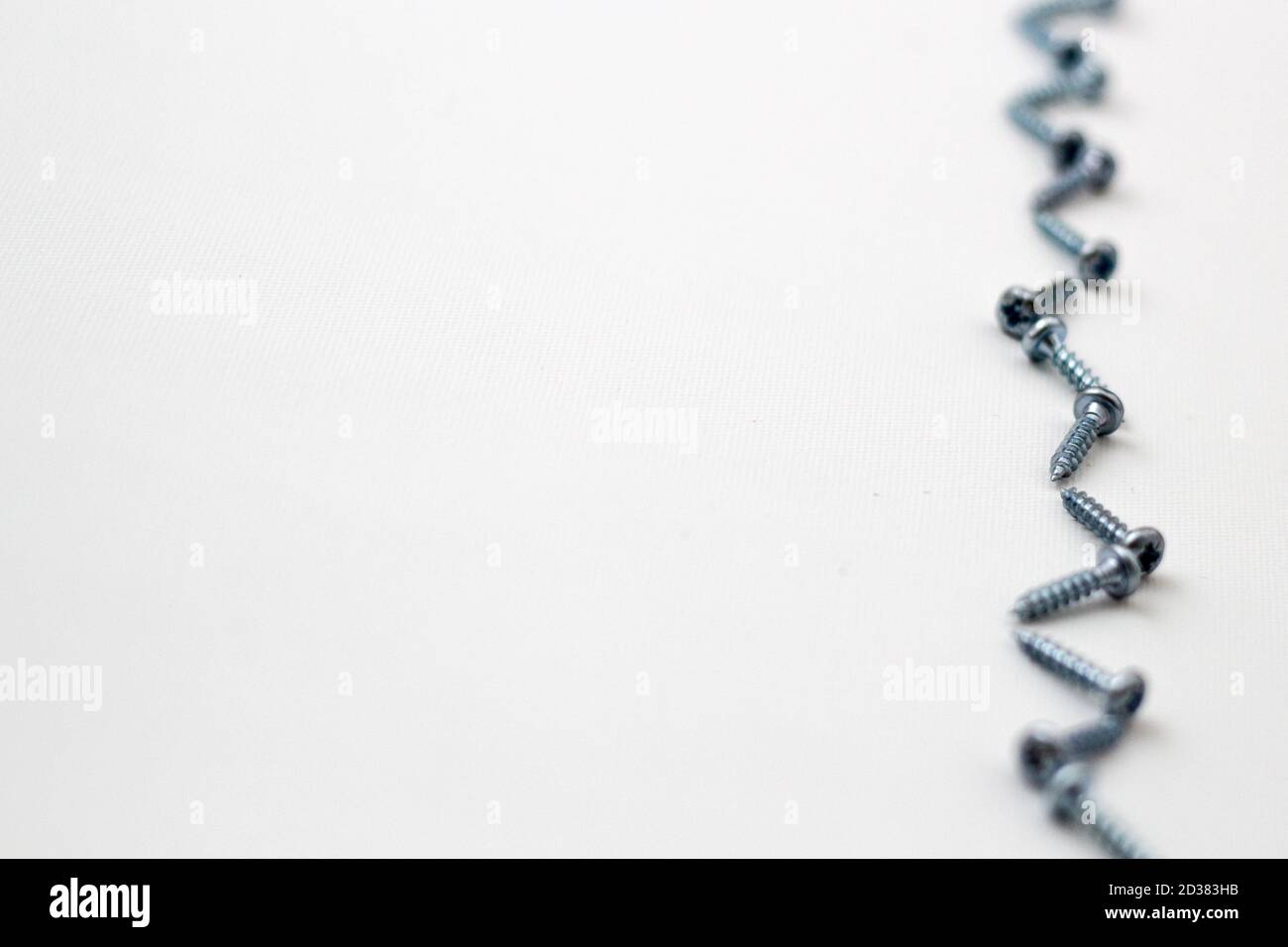 Soft focus of screws forming a line on white surface with space for ...