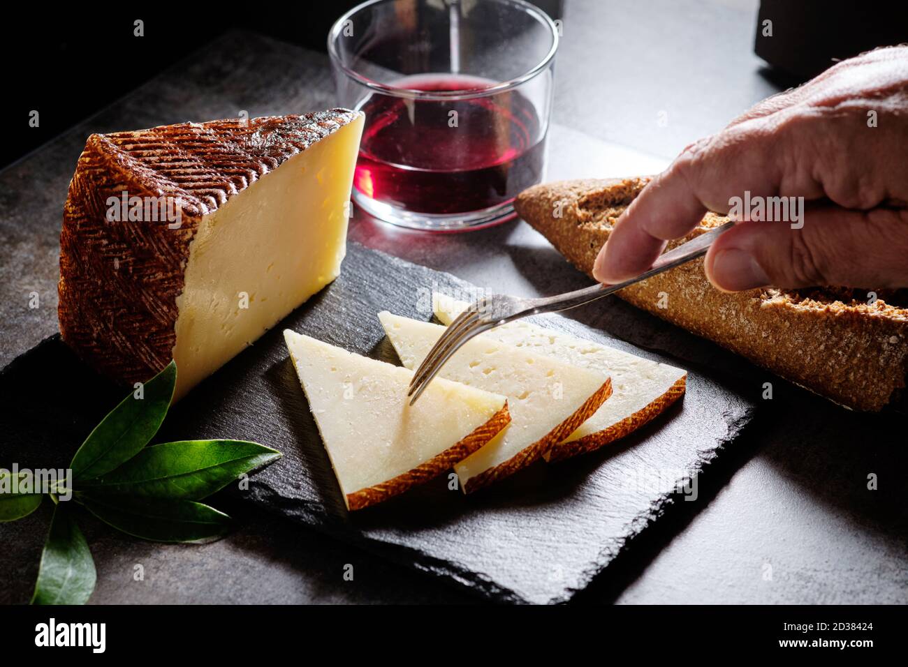 Hand pricking a slice of cured Manchego cheese with a fork Stock Photo ...
