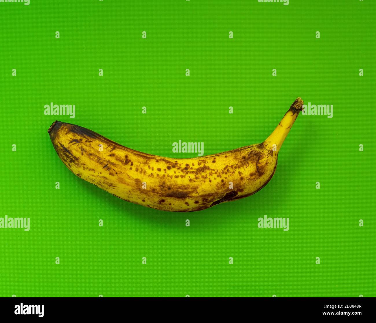 Single over ripe banana with a green background Stock Photo - Alamy
