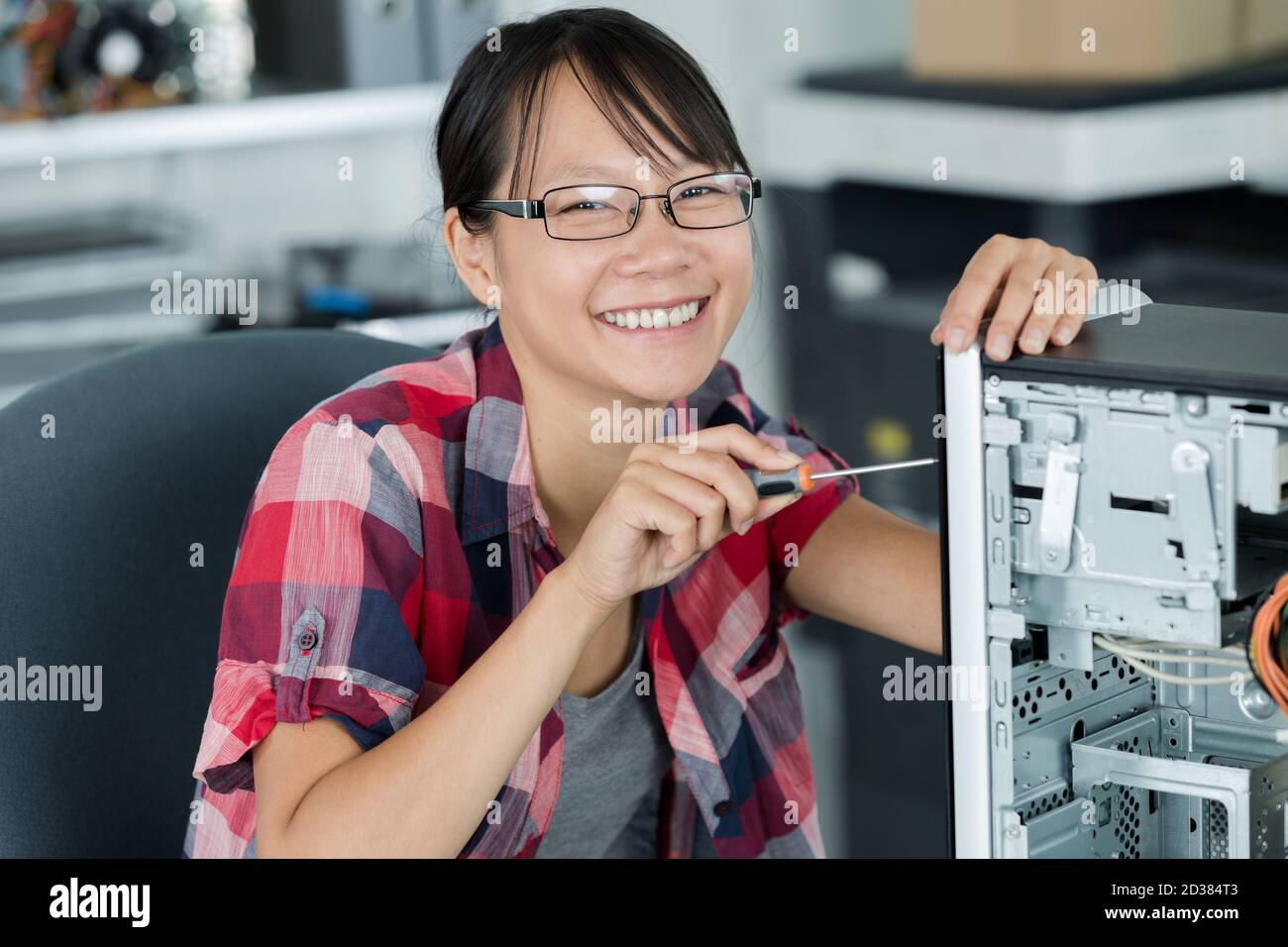 portrait of a smily woman fixing a computer at work Stock Photo - Alamy