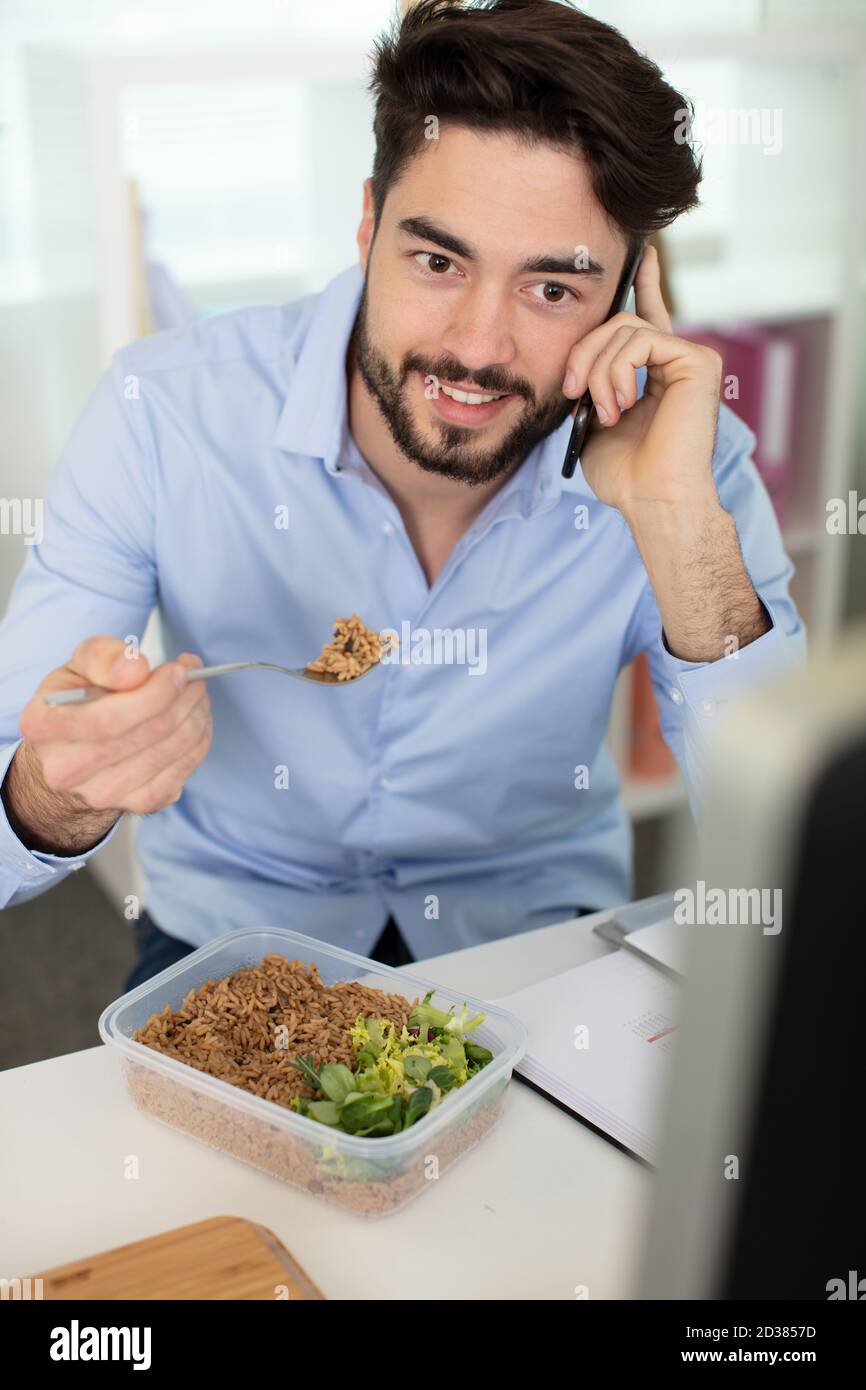 young business man talking on the phone while eating Stock Photo - Alamy