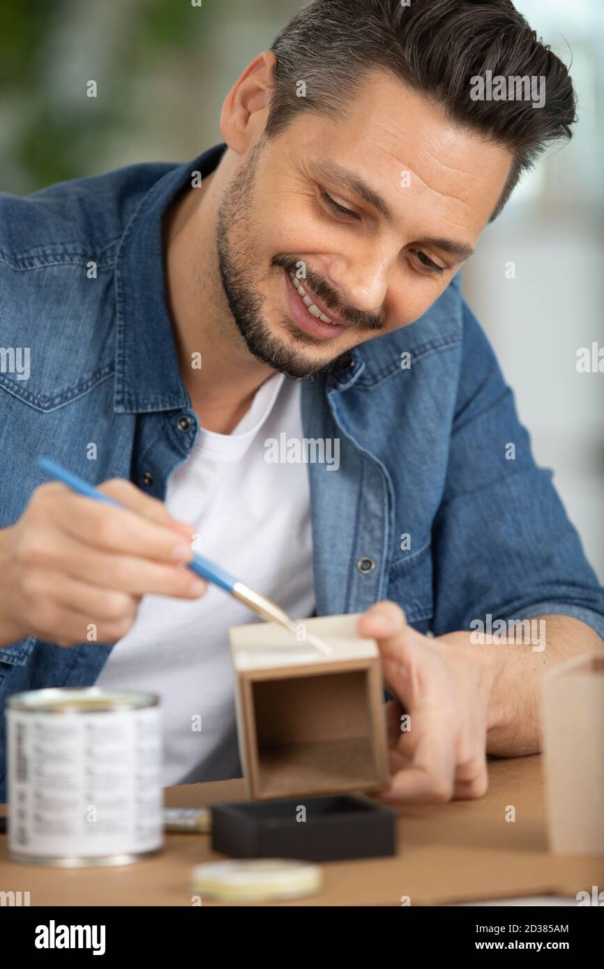 man painting a small wooden box Stock Photo - Alamy