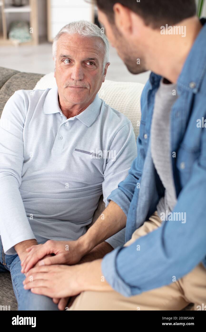 senior father sits on couch taking to song Stock Photo - Alamy