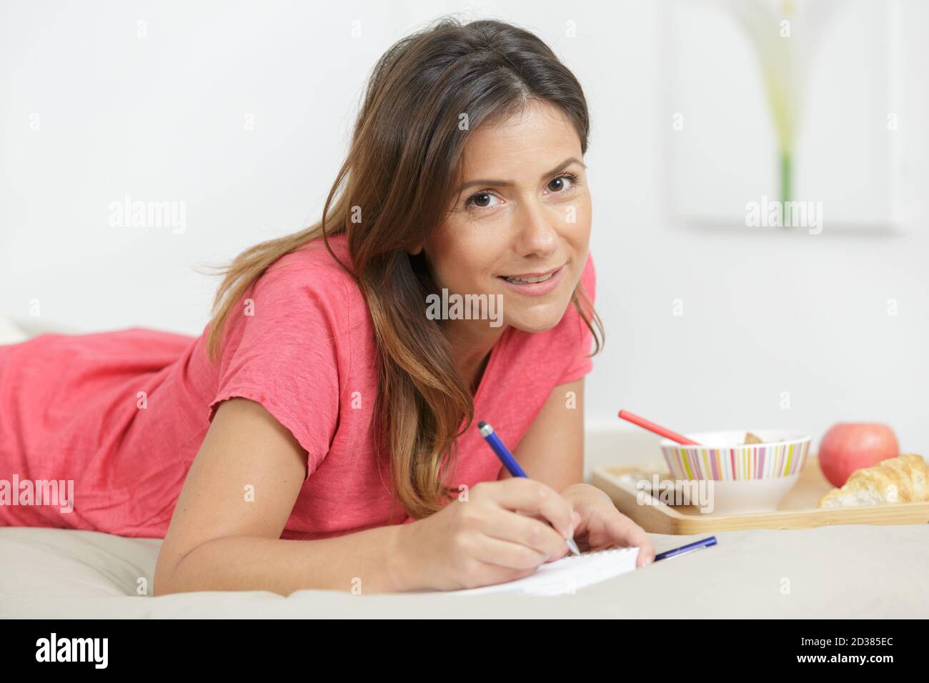 woman layed on her bed writing a list Stock Photo - Alamy