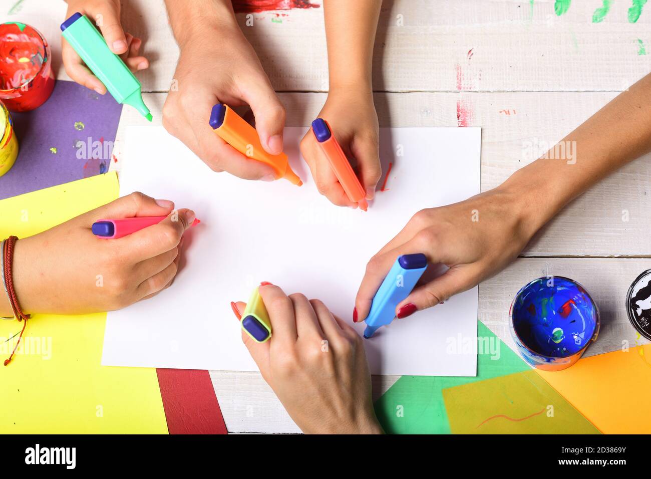 Hands hold colorful markers and draw, top view. Markers in male and ...