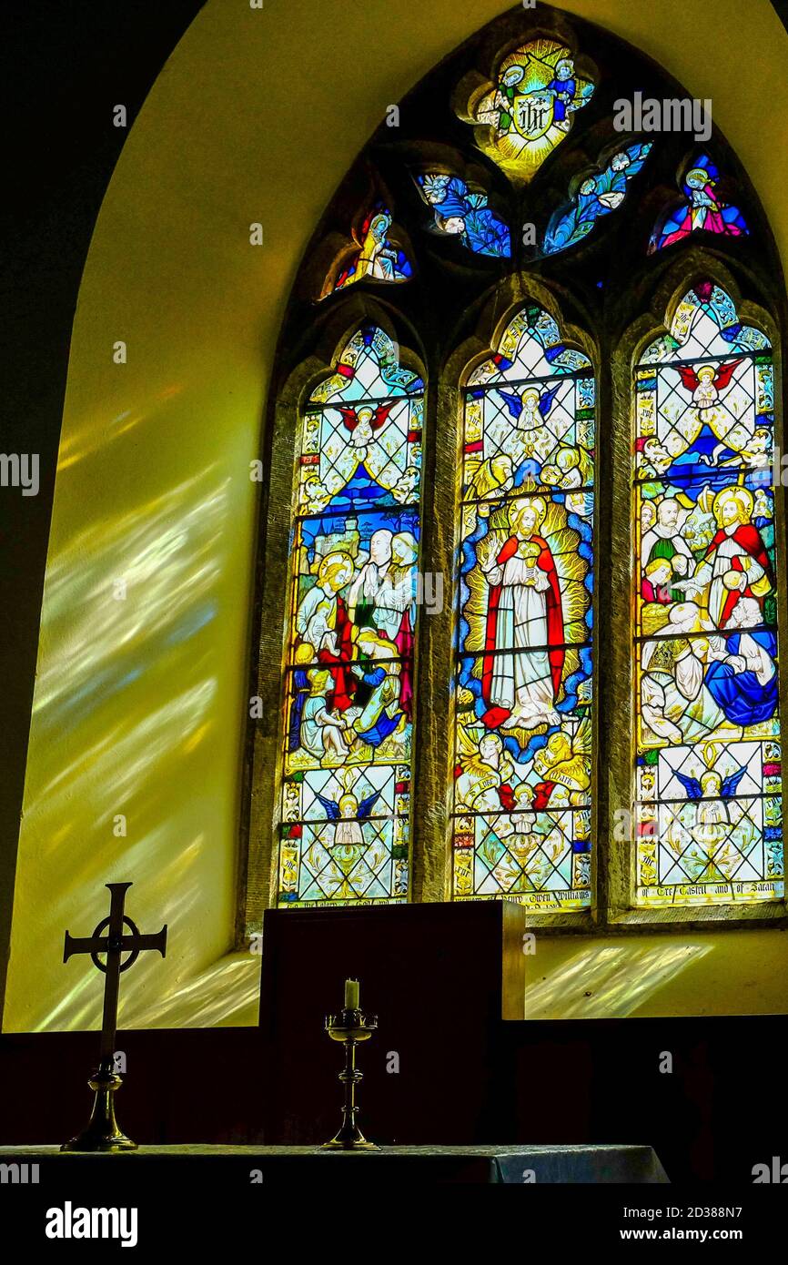 Light streaming through stained glass window at Penmon Priory ...