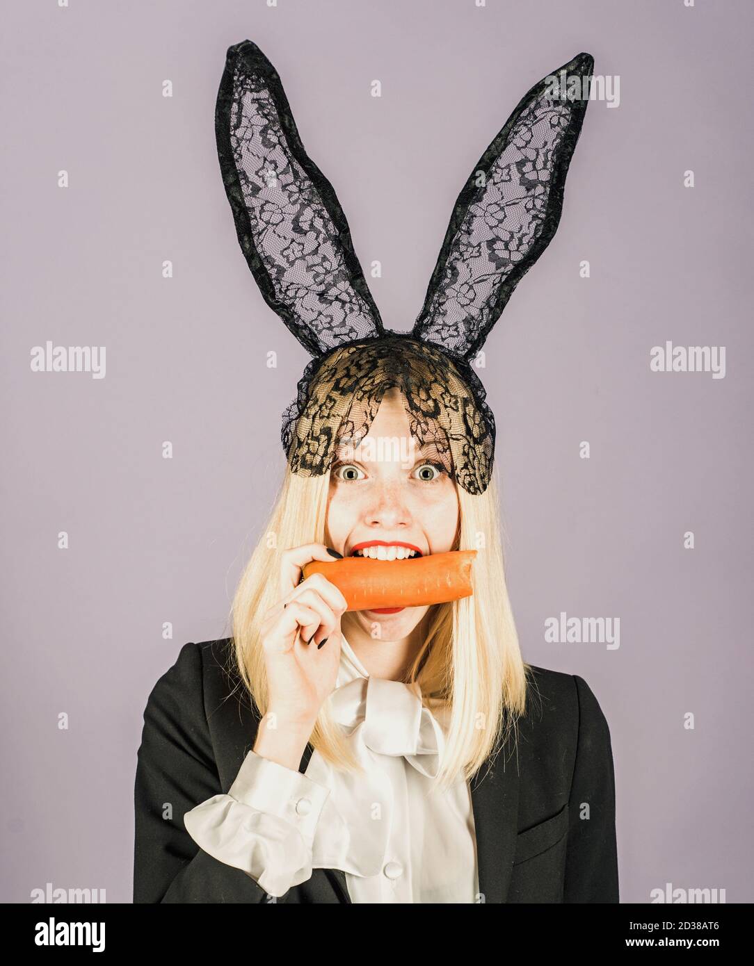 Surprised bunny woman wearing bunny ears and eat carrot. Happy easter ...