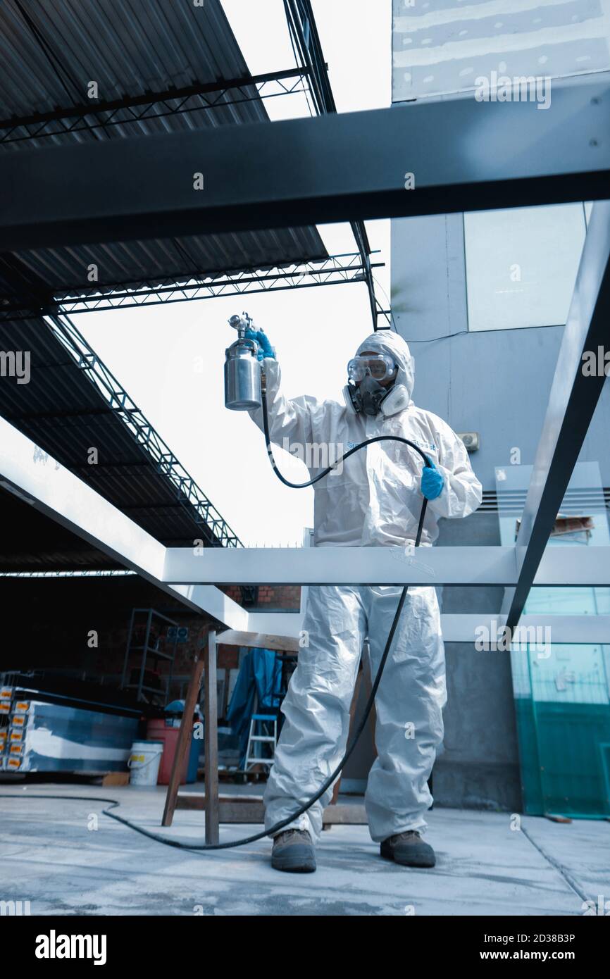 Vertical shot of a worker in a hazmat painting wooden details Stock ...