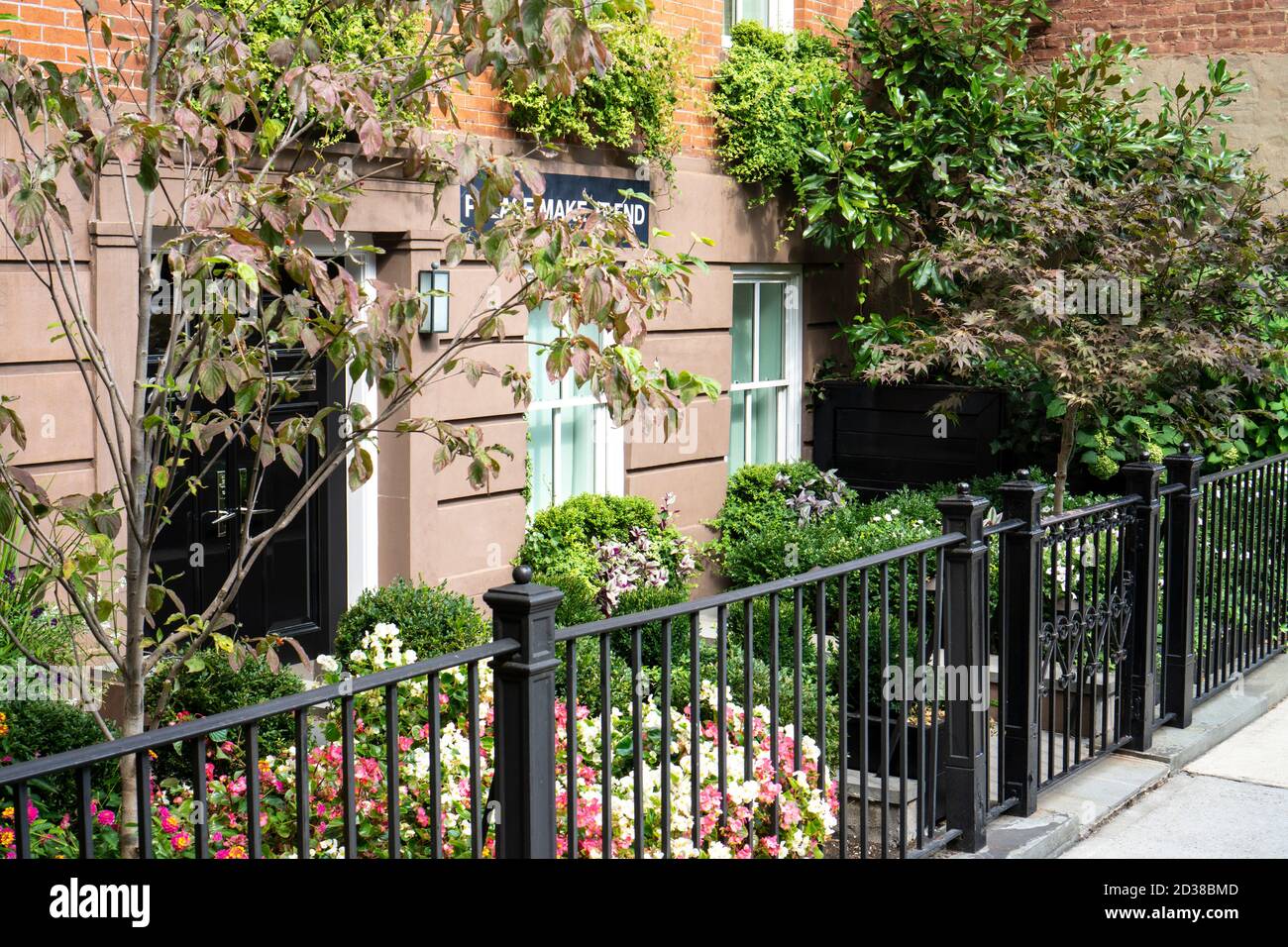 Plants and flowers in bloom behind a fence in front yard of a house ...