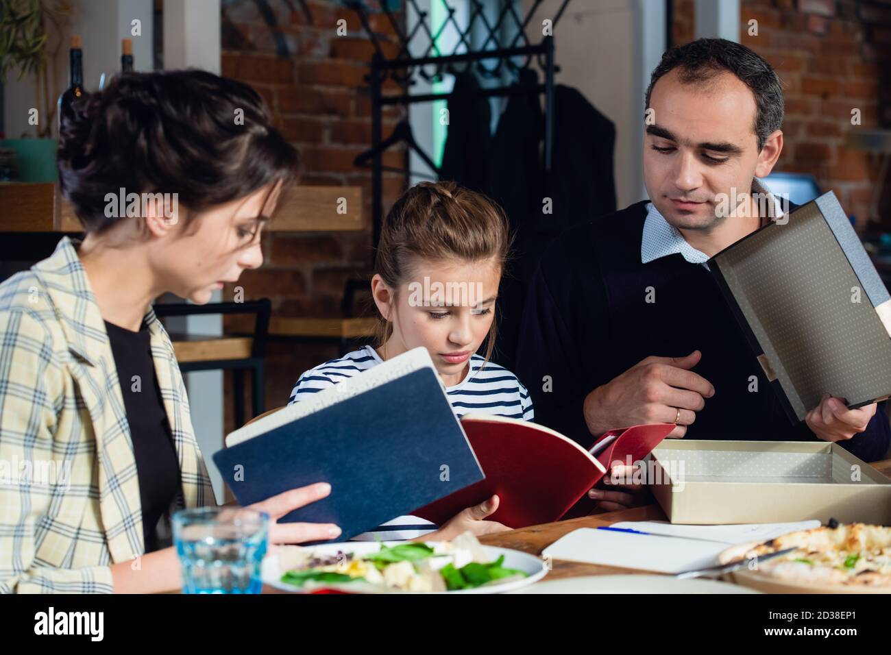 A girl doing her homework at the kitchen table with her parents being ...