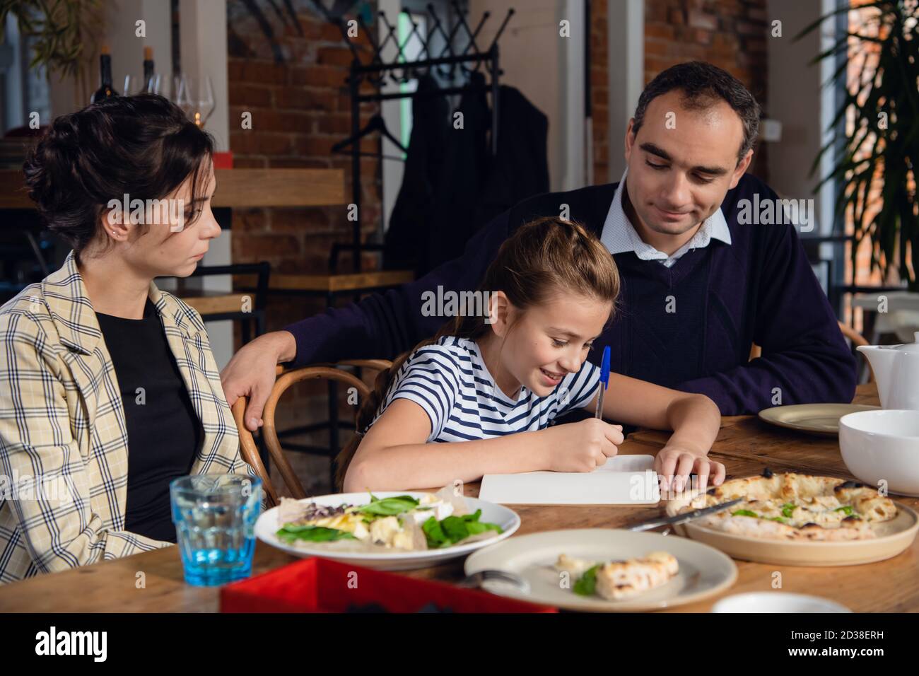 Young parents helping their daughter with her homework Stock Photo - Alamy
