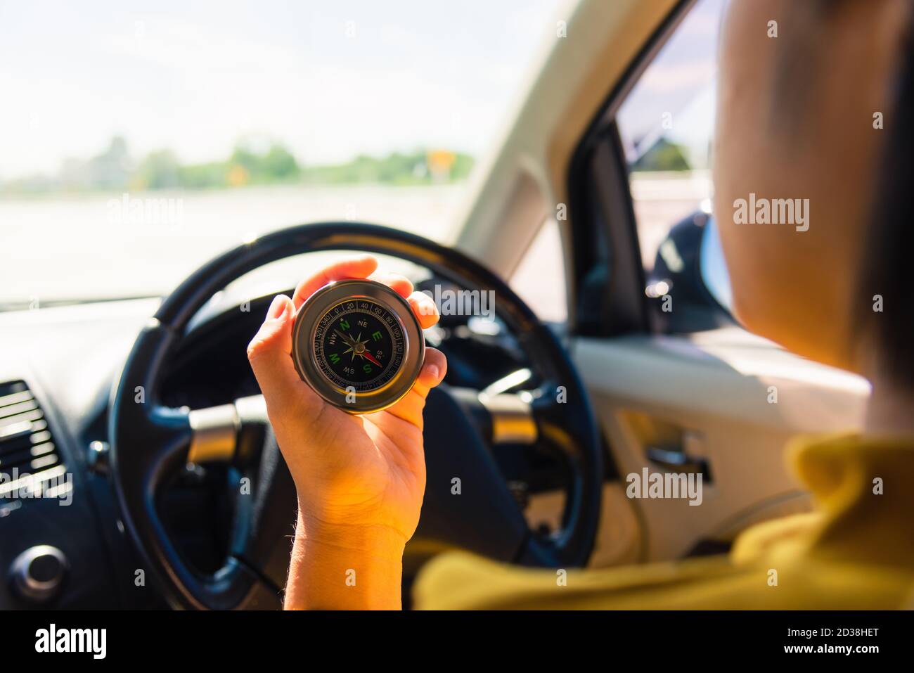 Asian woman inside a car and using compass to navigate while driving ...