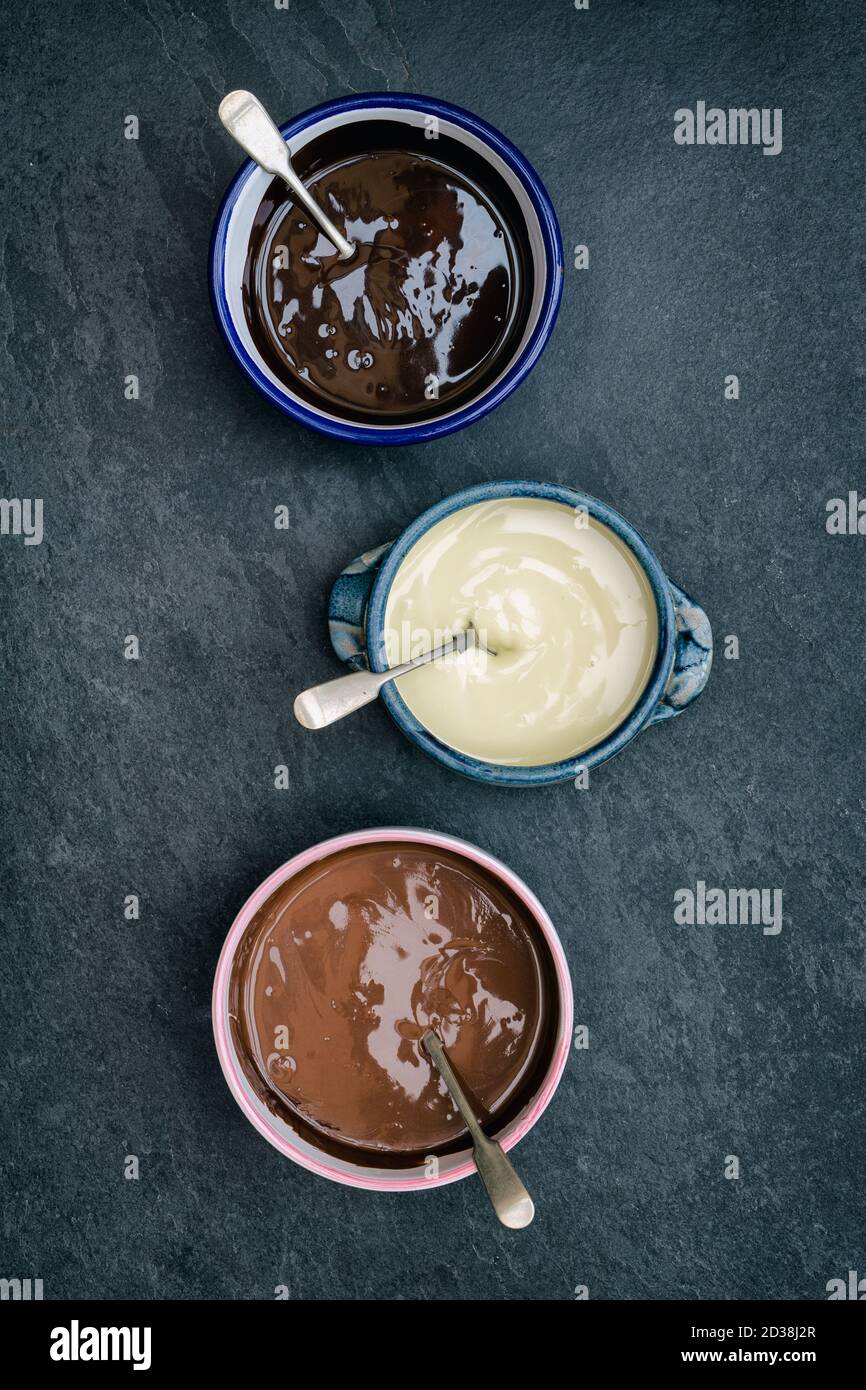 Three types of melted chocolate in bowls. Dark chocolate, milk ...