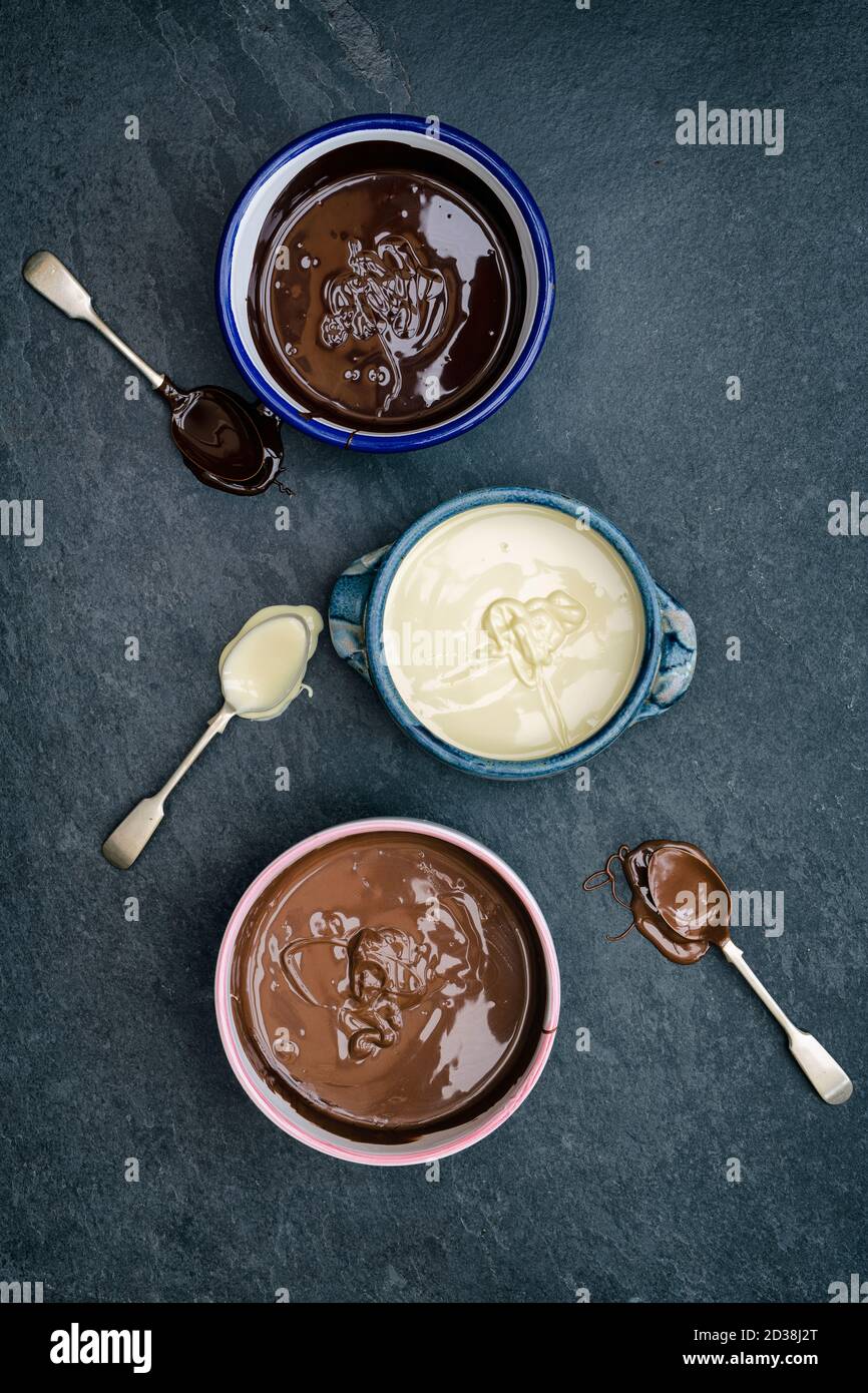 Three types of melted chocolate in bowls. Dark chocolate, milk ...