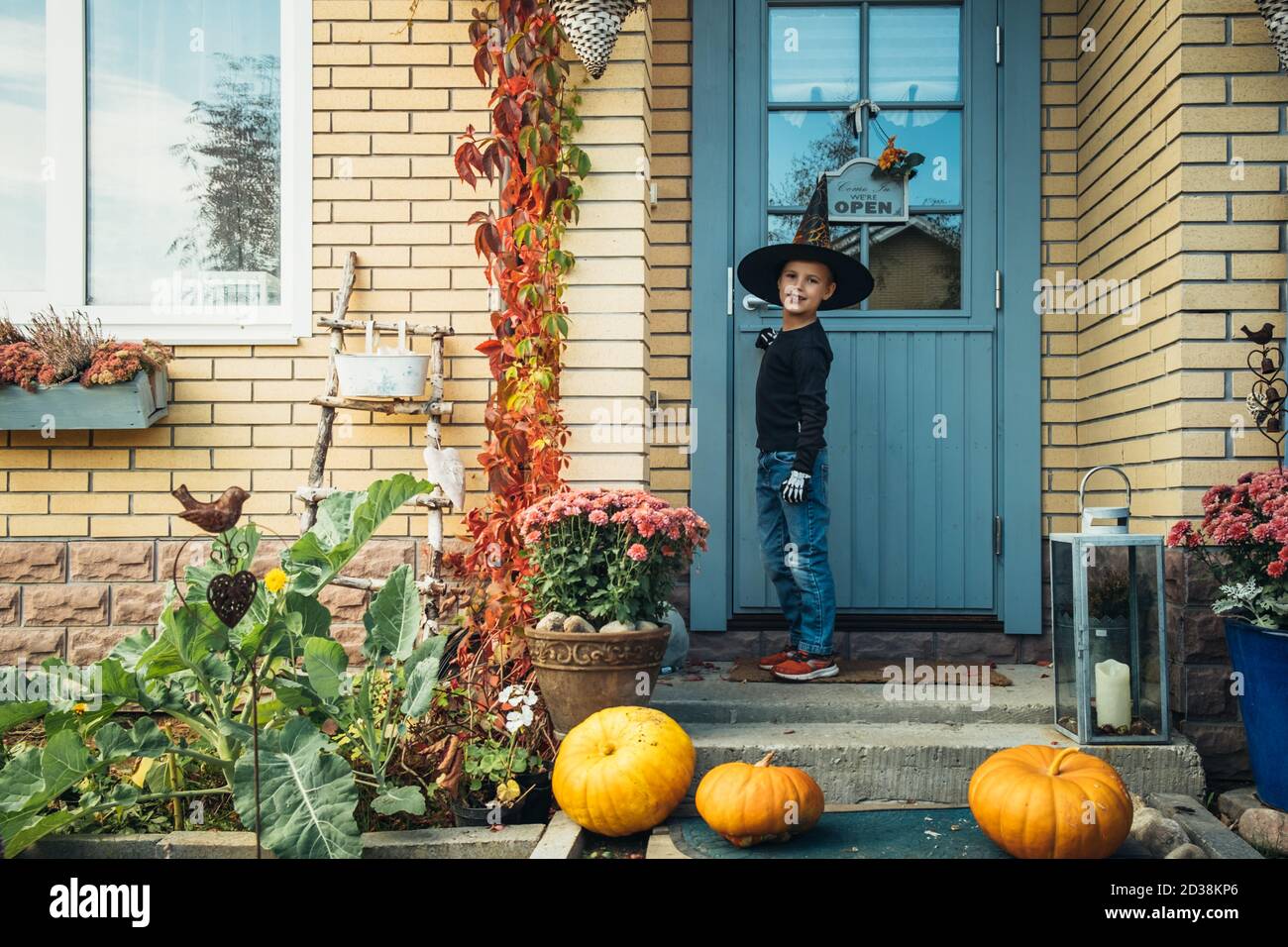 The boy knocking at the beautiful house with pumpkins in costumer hats ...