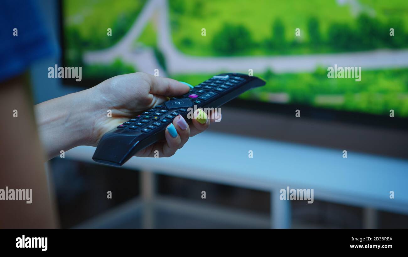 Lady holding TV remote control and pressing the button. Close up of ...