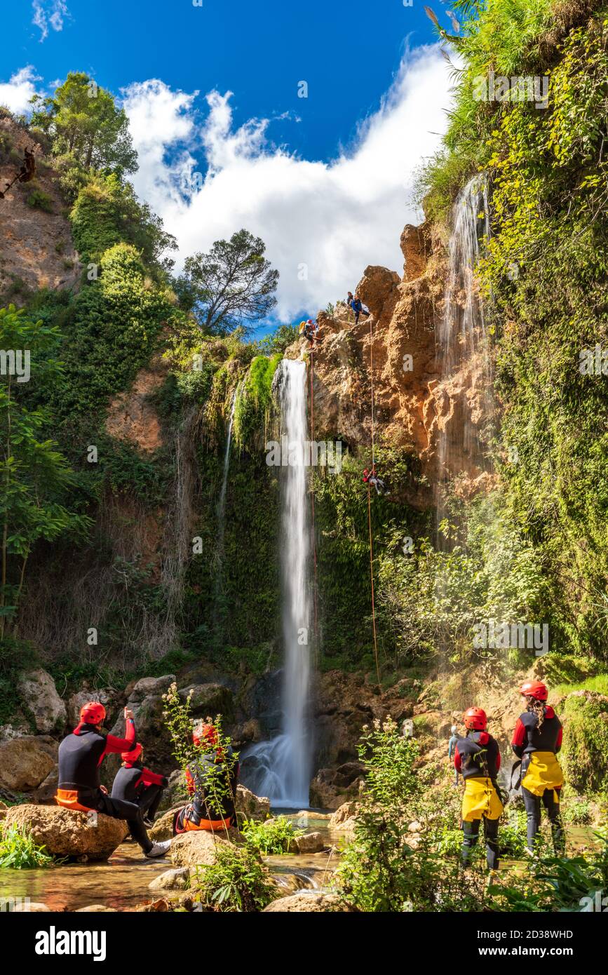 Large group enjoy waterfall descent using ropes Stock Photo - Alamy