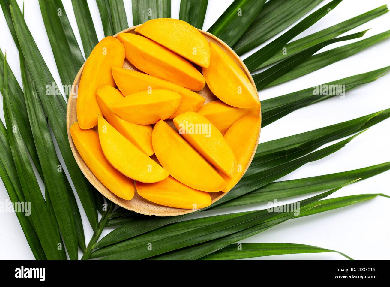 Mango slices on wooden plate on tropical palm leaves Stock Photo - Alamy