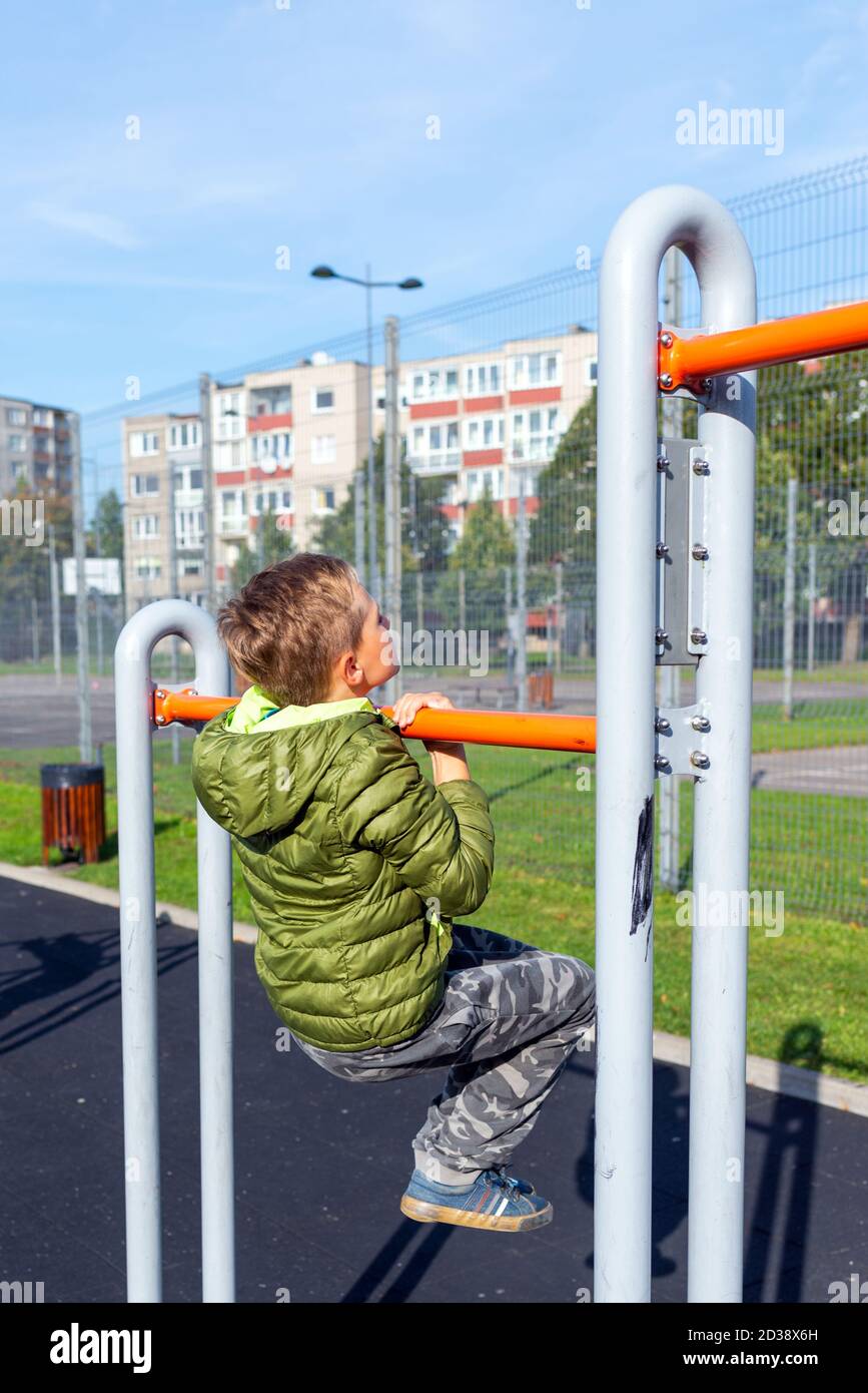 Side view Young Boy kid child 9s in casual clothes performing pull-ups ...