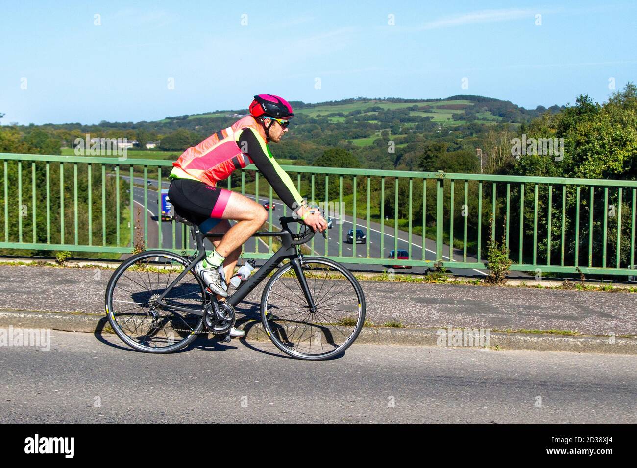Male cyclist riding sports road bike on countryside route crossing ...