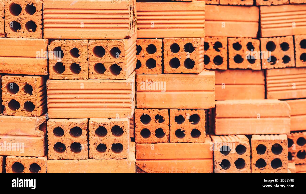 Close up pile new red brick with holes stacked in rows wall. Store of ...