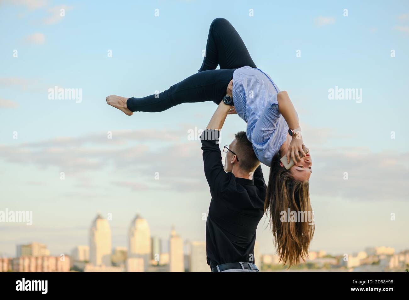 Base acroyoga partner hold female flyer up while she talk by mobile ...